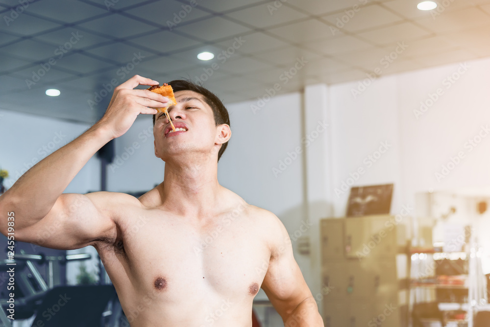 Young strong muscular athlete sporty man eating unhealthy junk fast ...