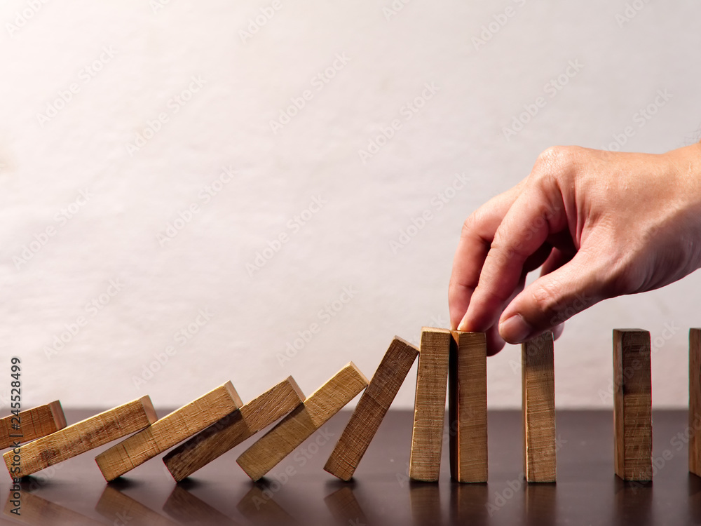 Hand stopping the domino wooden brick from falling continuous toppled ...
