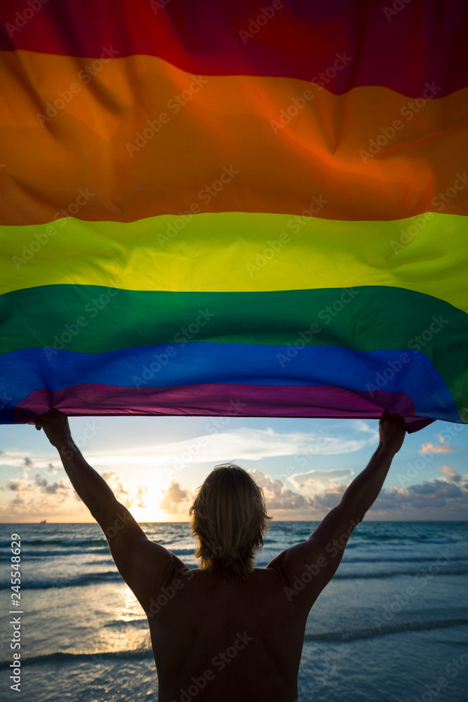 Colorful sunset silhouette of a man with blond hair holding a rainbow ...