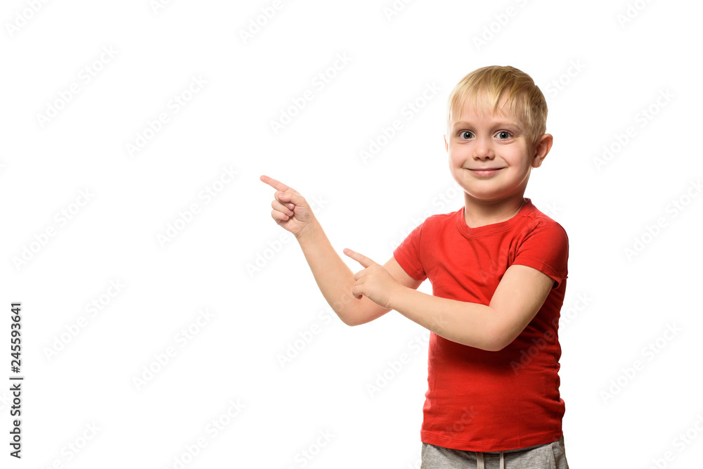 Smiling little blond boy in a red shirt stands and shows index fingers ...