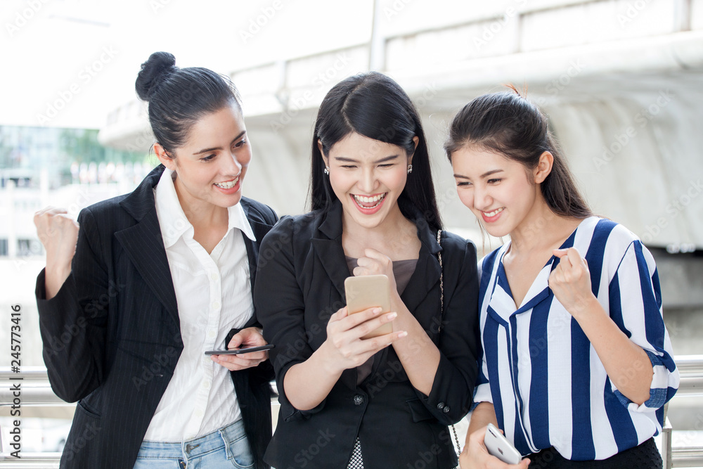 group of beautiful young women friends using a smart phone and laughing ...