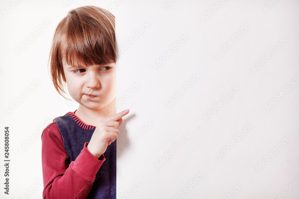 Serious little child girl pointing from the side at the white board ...
