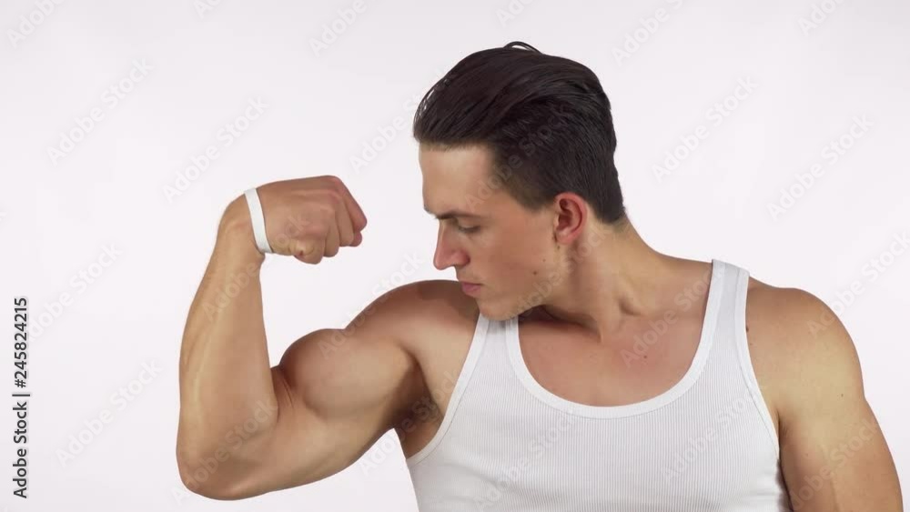 Muscular young man flexing his bicep looking to the camera fiercely ...