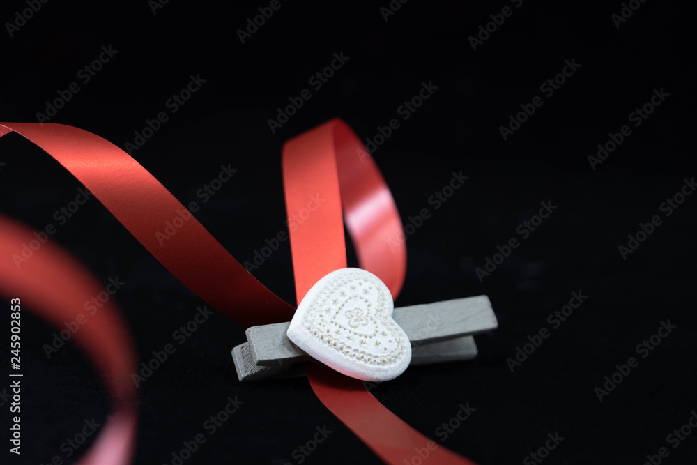 Pince avec un coeur en céramique blanche tenant un ruban cadeau rouge ...