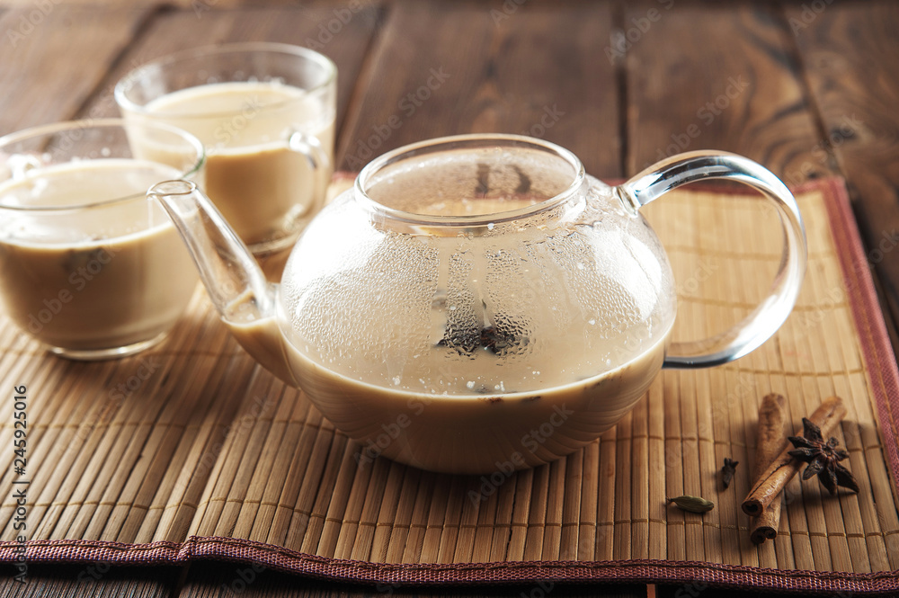 Masala tea on a textural wooden background. A teapot is a transparent ...