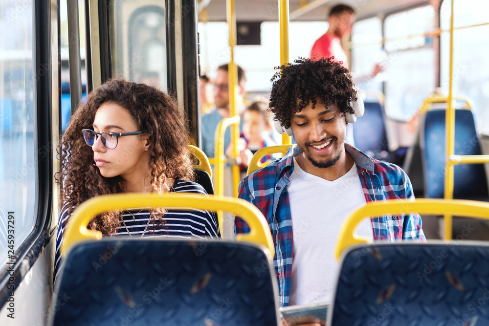 Two young persons sitting next to each other in city bus. Girl looking ...