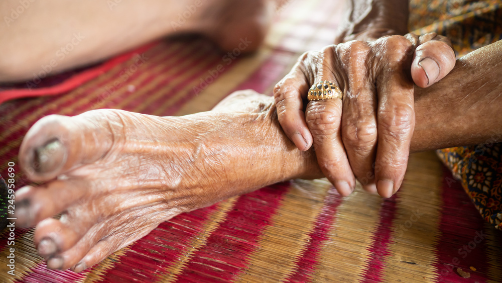 Focus on the feet and hands of the old woman sitting on the mat. She ...