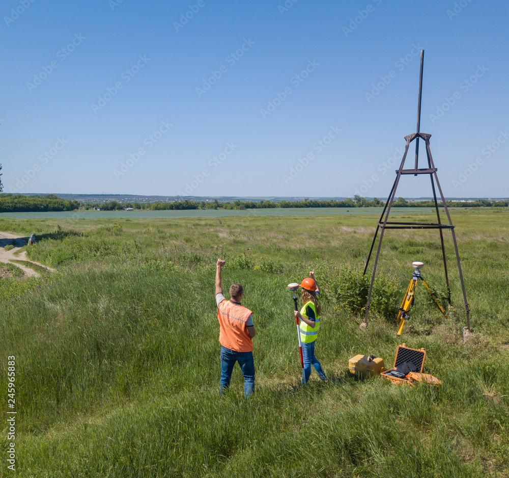 Two Land Surveyors Engineers are Working on the Green Field. Male and ...