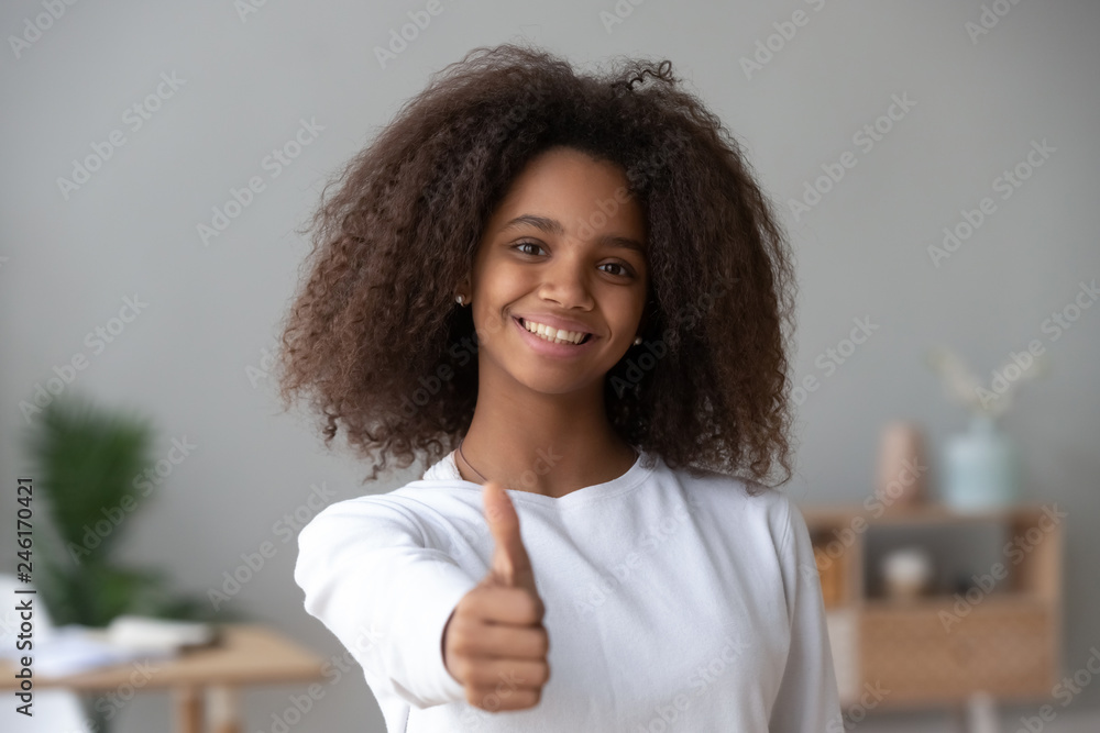 Happy African American teenage girl looking at camera, showing thumbs ...