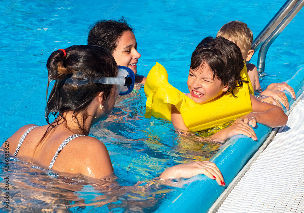 A smiling boy and two girls are swimming in a pool in a water park ...