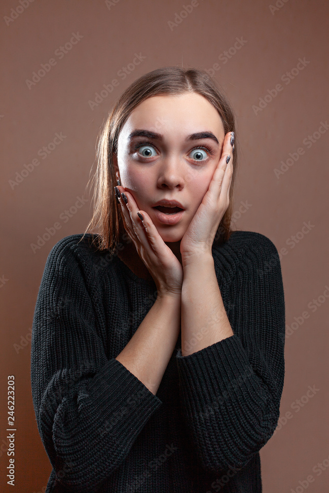 Beautiful young woman with an expression of fear, on a beige background ...