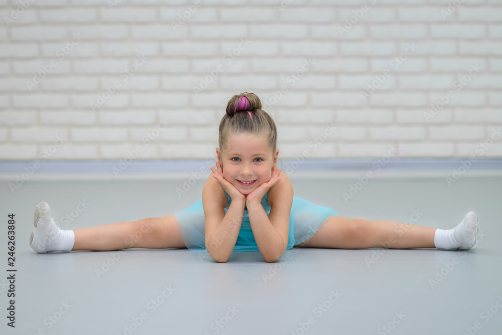 Cute little beautiful girl doing splits at ballet class. Young happy ...