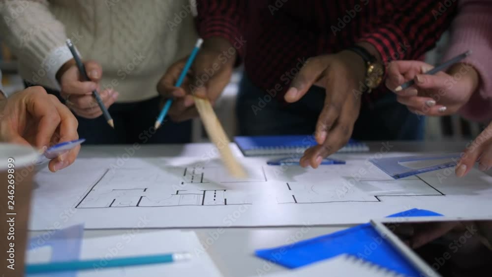 Close-up of diverse hands blueprinting plan of new building with ...
