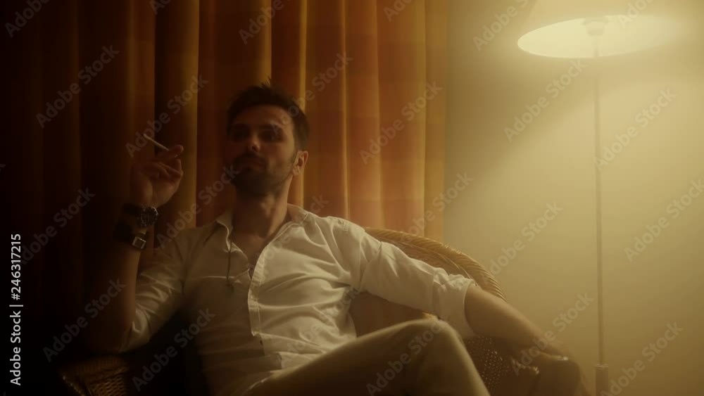 Man Sits In A Chair And Smoking Cigarette.Man Wearing In White Sits In ...