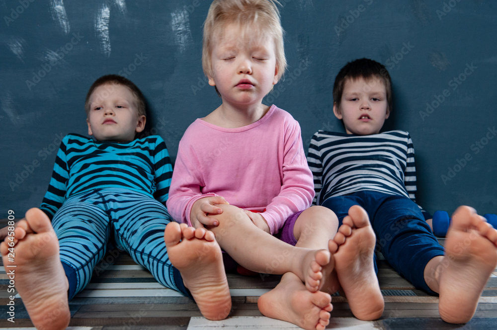 Three children are sitting on floor in room and are going to do ...