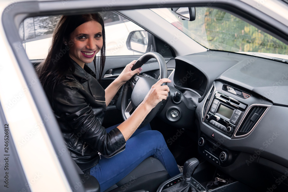 Beautiful smiling female driver in black jacket sitting inside car and ...