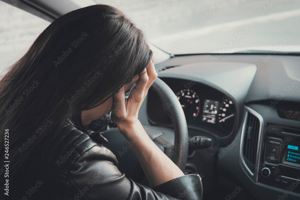Stressed woman driver sitting inside her vehicle. Brunette girl doing ...