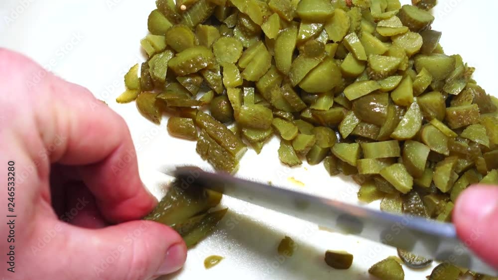Cutting pickles on white cutting board, close up, nobody, male hands ...
