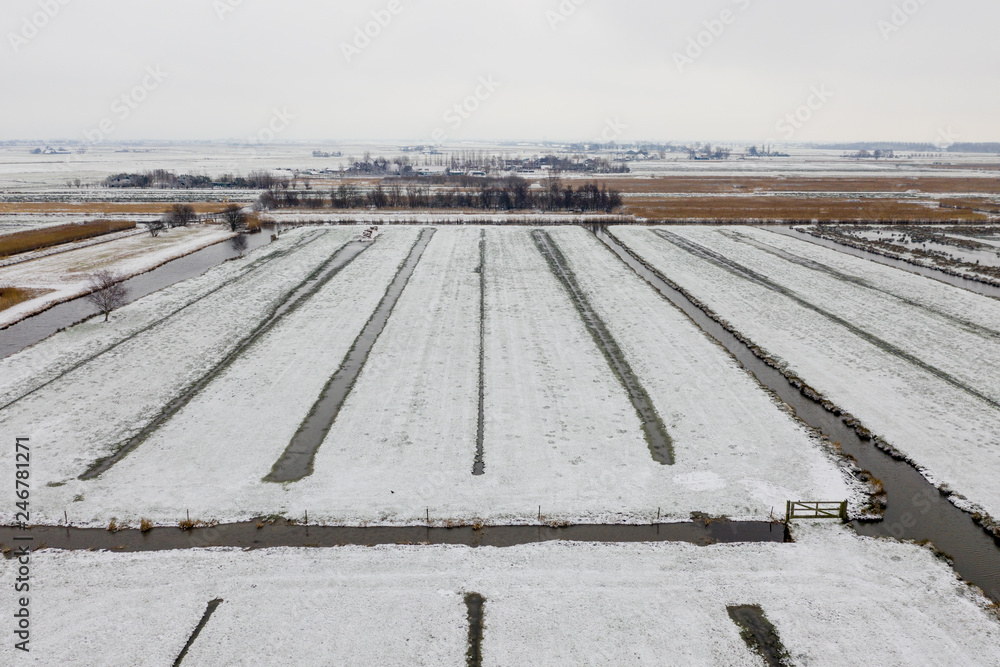 Agricultural fields covered with a thin layer of snow. Tiny canals used ...