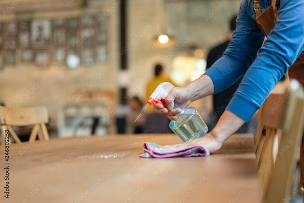 Waiter cleaning the table with spray disinfectant on table in ...