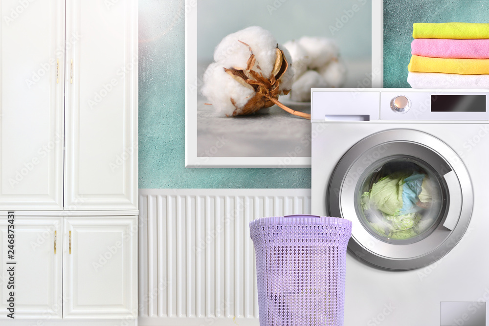 Laundry room interior with washing machine, basket, cotton towels ...