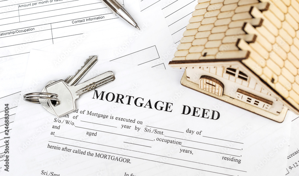 House Keys with pen and model of house on mortgage deed form. Close up ...
