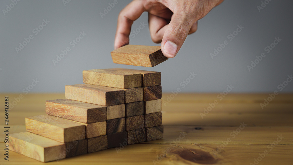 Closer up hands of businessmen,stacking wooden blocks into steps ...