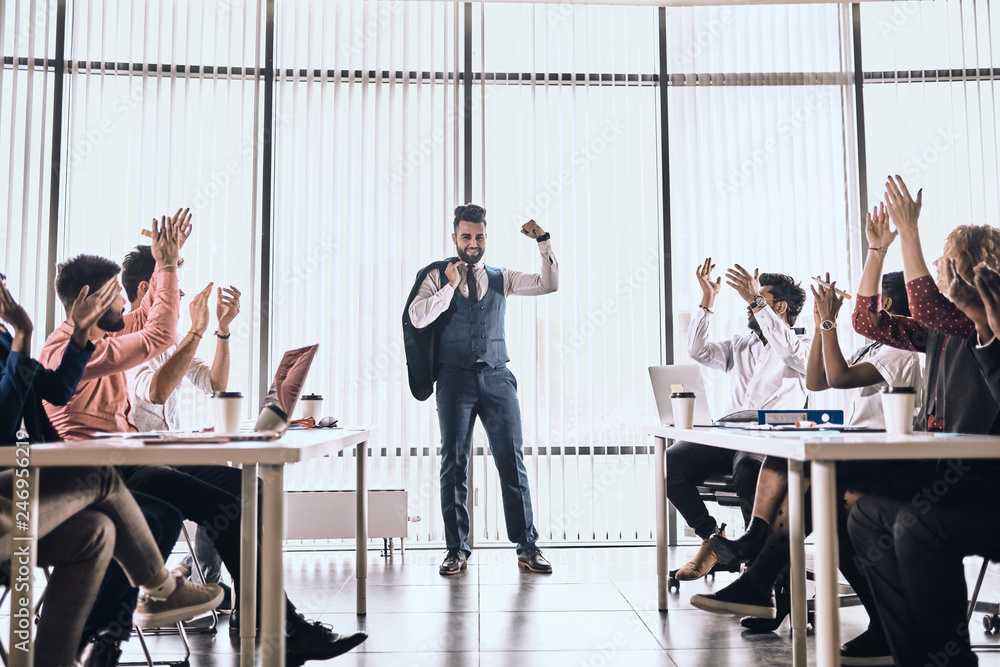 leader of team showing his biceps while colleagues are applouding him ...