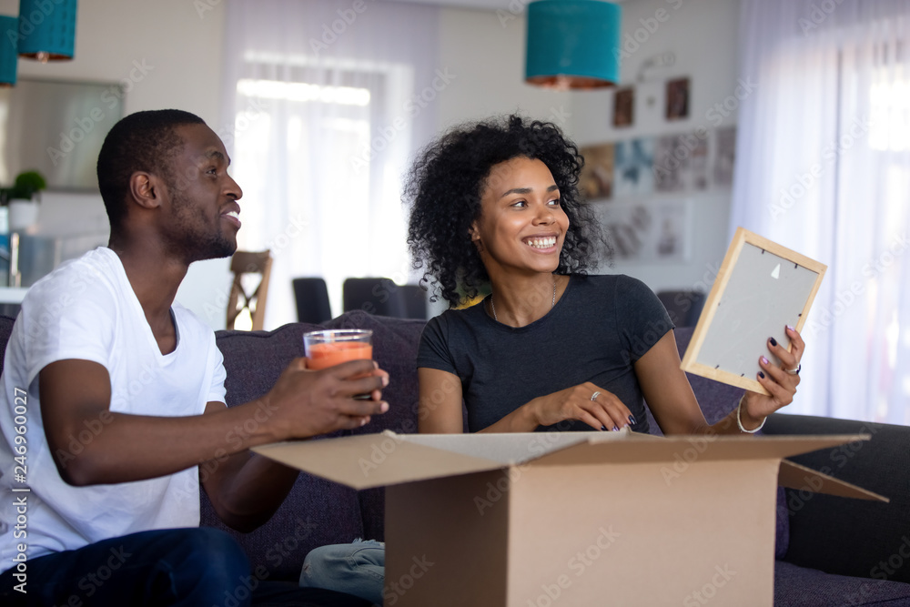 Happy african couple having fun unpacking in living room on moving day ...
