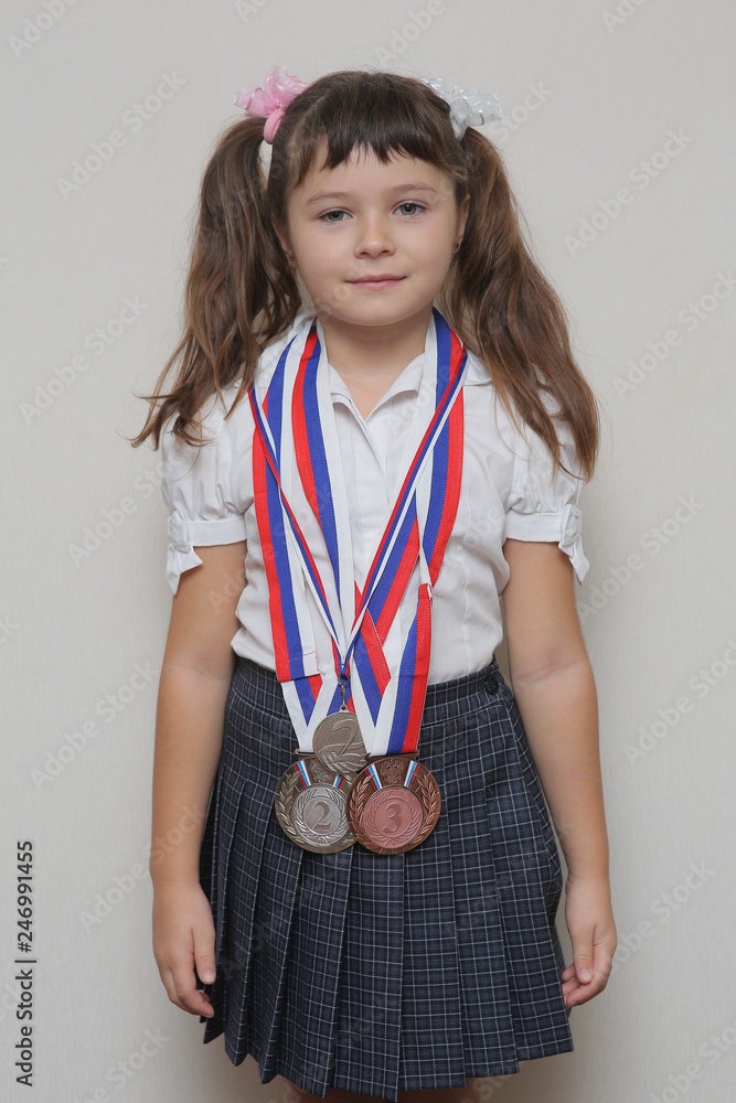 schoolgirl with two tails in school uniform with a lot of medals on her ...