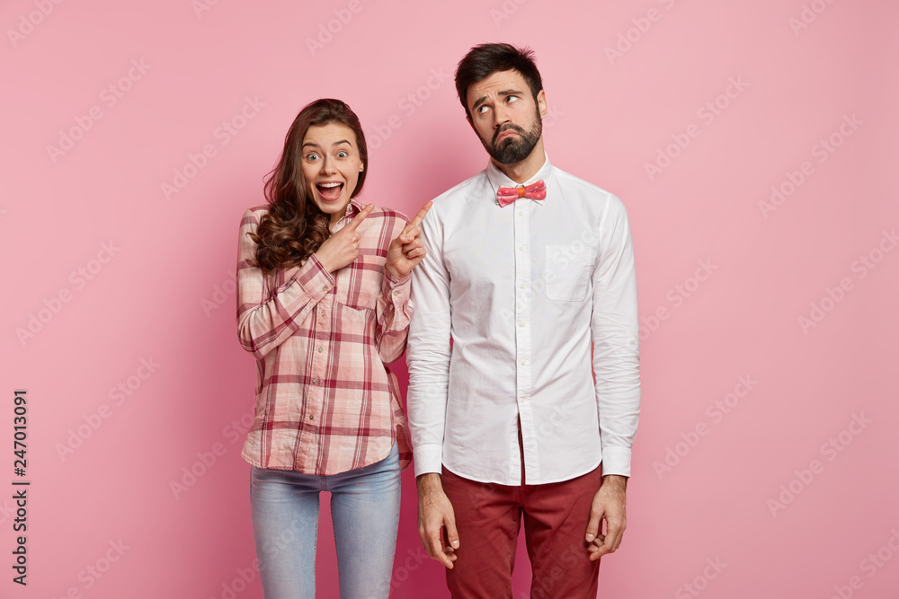 Half length portrait of happy woman indicates at unsuccessful man who ...