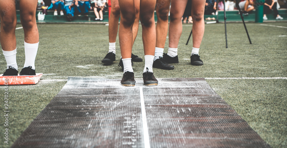Students boy taking long jump on rubber board pid or sand pid during a ...