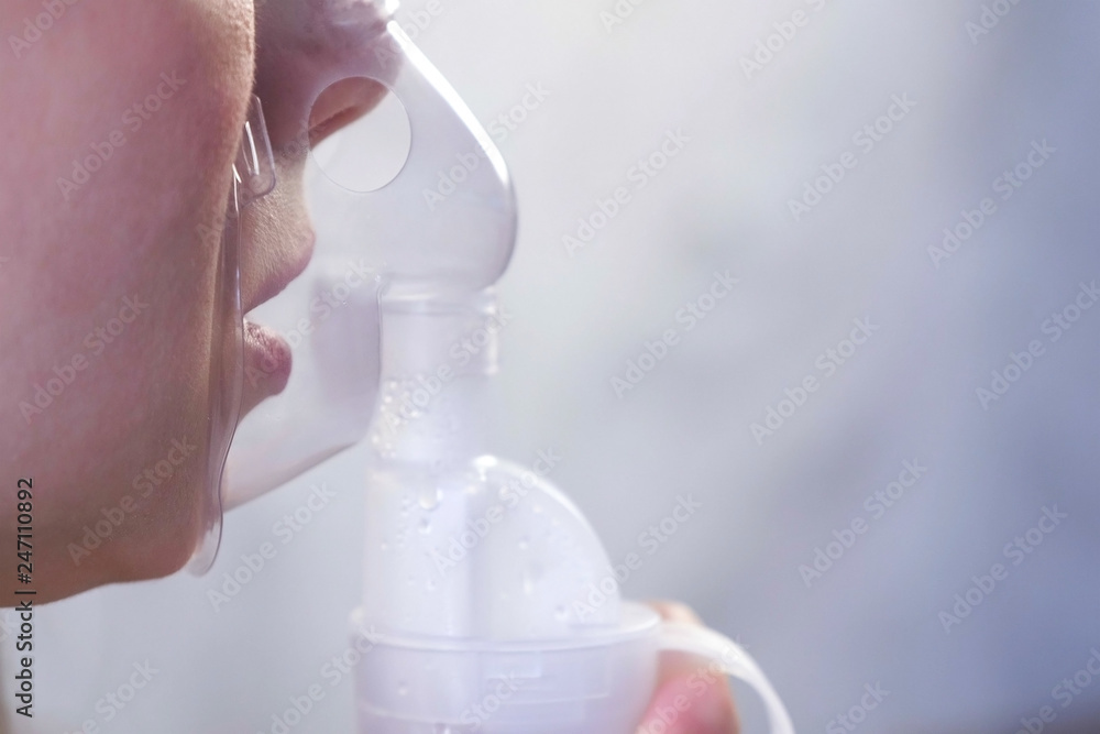 Use nebulizer and inhaler for the treatment. Young woman inhaling ...