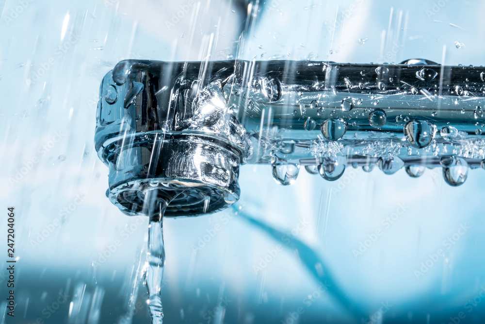 Water flows from a modern chromed water tap faucet macro close-up ...