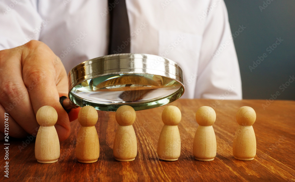 Performance review. Man with magnifying glass evaluate figurines as ...