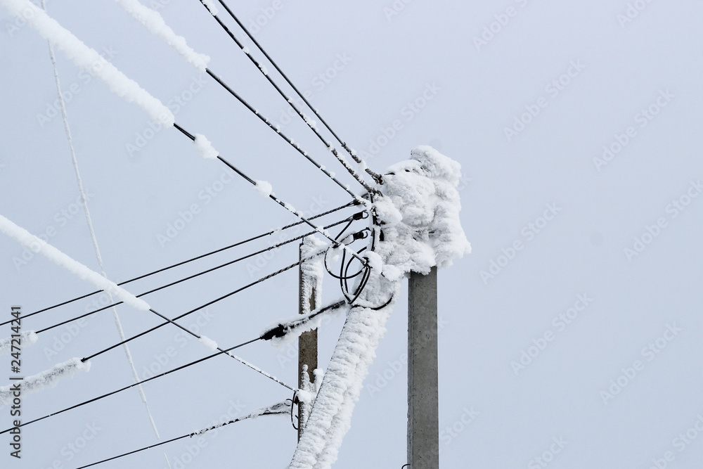 power line on a pole of many wires covered with a thick layer of snow ...