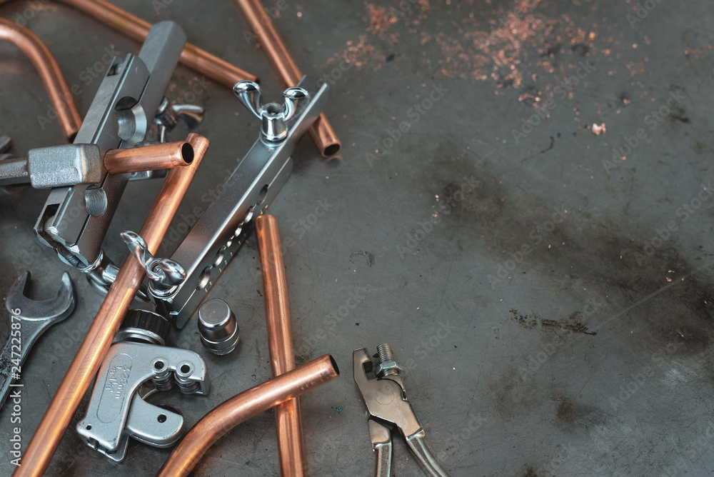Pipe rammer, cutter, pliers, wrench and brass pipes on a fitter ...
