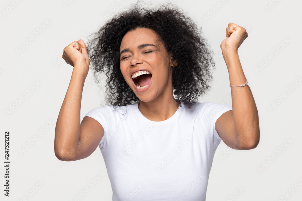 Overjoyed young african american woman screaming with joy celebrating ...