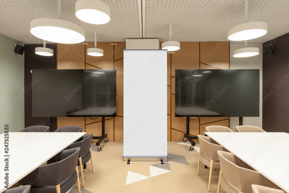 Blank roll up banner stand in modern office meeting room with blank ...