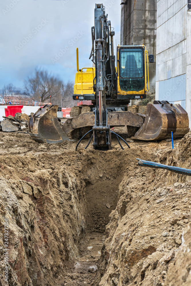 Excavator with a drill making a narrow ditch to put gas pipes Stock ...