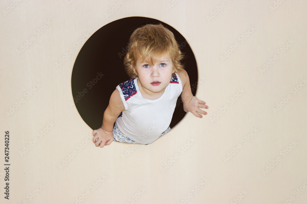 Cheerful joyful playful curious little kid boy half climbed out into ...