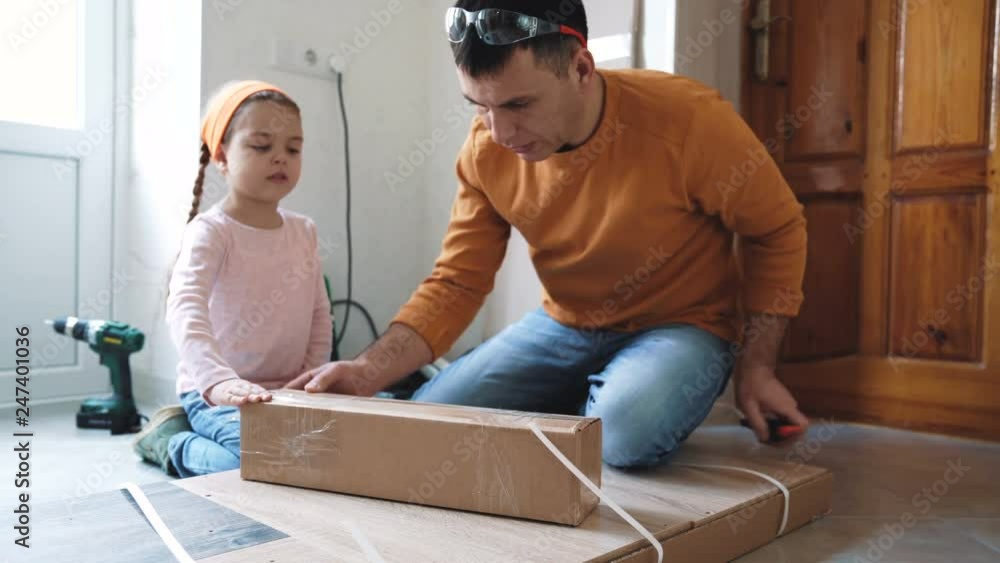 A father with his beautiful little daughter opens a package with new ...