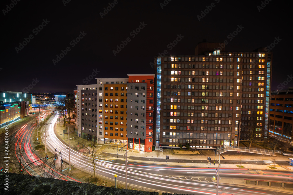 Traffic light trails passing skyscraper buildings in city at night ...