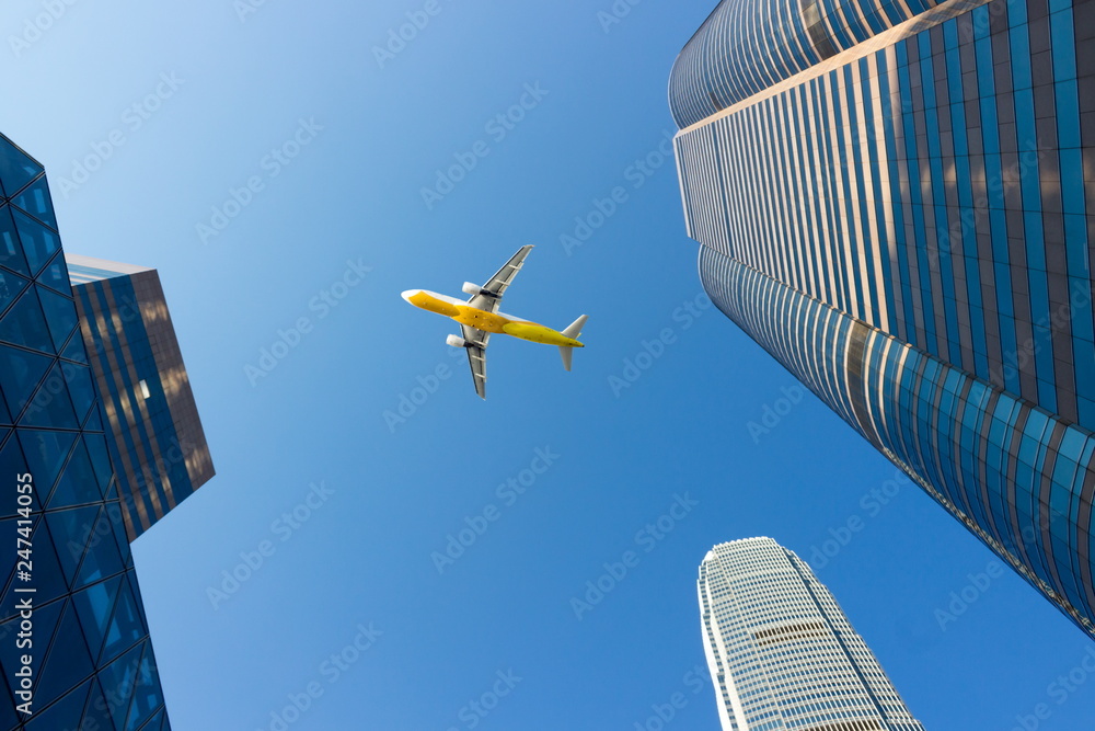 Airplane in sky and modern office buildings downtown. Viewed from below ...