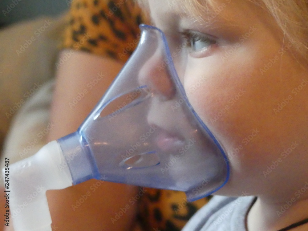 The boy breathes through an oxygen mask. The child takes inhalations ...