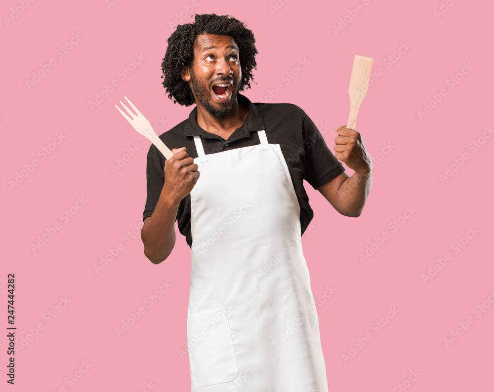 Handsome african american baker screaming happy, surprised by an offer ...