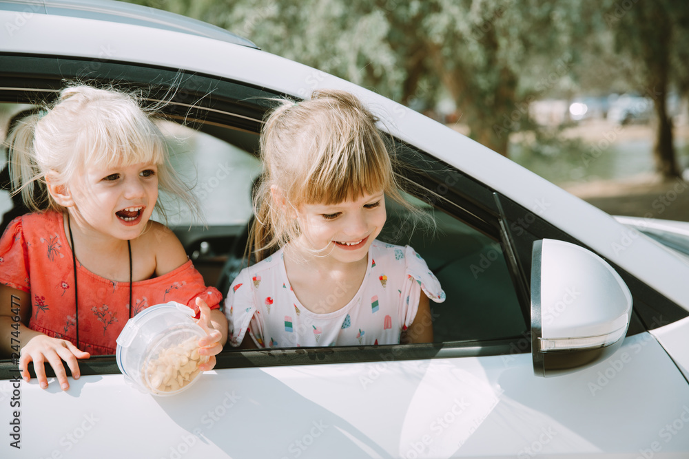 Funny little girls sticking heads out car window. Traveling by car with ...
