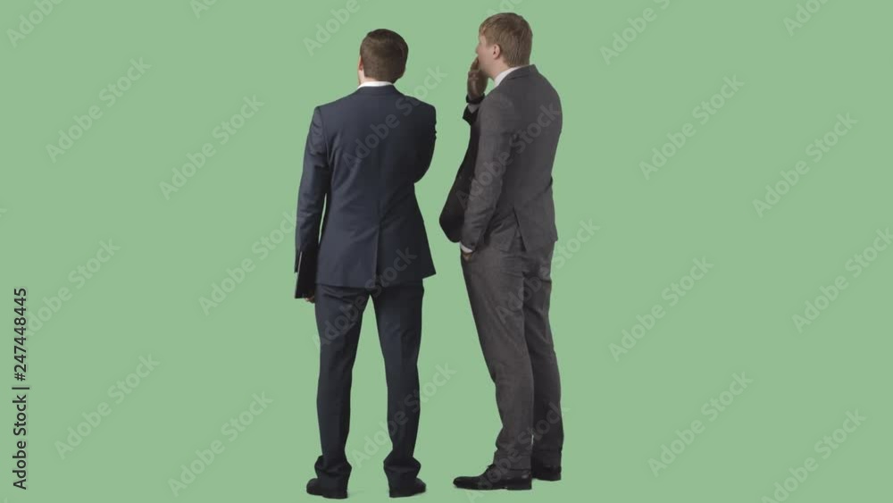 Two men in business clothes are looking at something in front of them ...