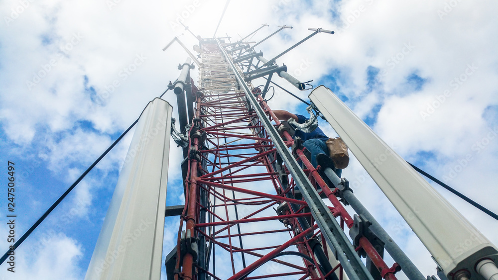 Worker climbing on a very high metal construction radio cellular ...