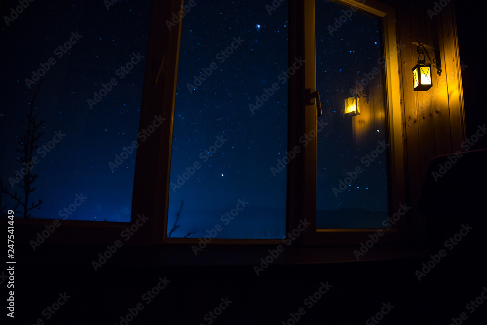 Night scene of stars seen through the window from dark room. Night sky ...